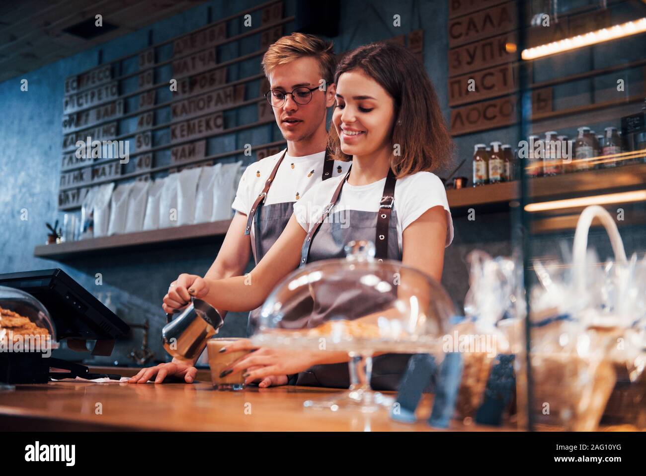 Behind the bar. Two young cafe workers indoors. Conception of business ...