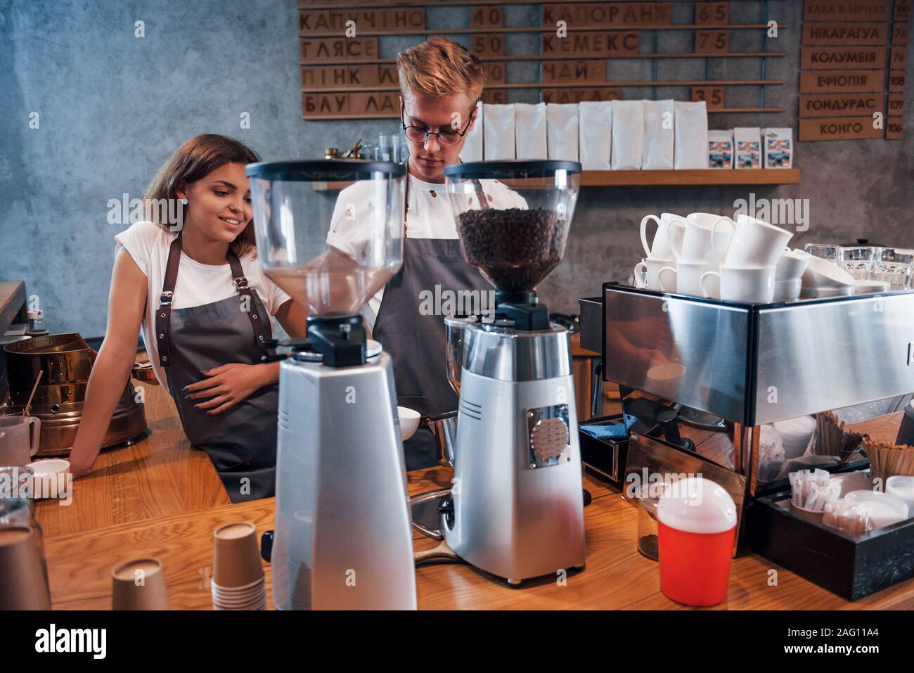 Behind the coffee machine. Two young workers indoors. Conception of ...