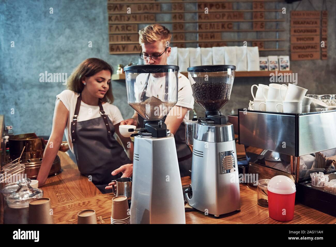 Behind the coffee machine. Two young workers indoors. Conception of ...