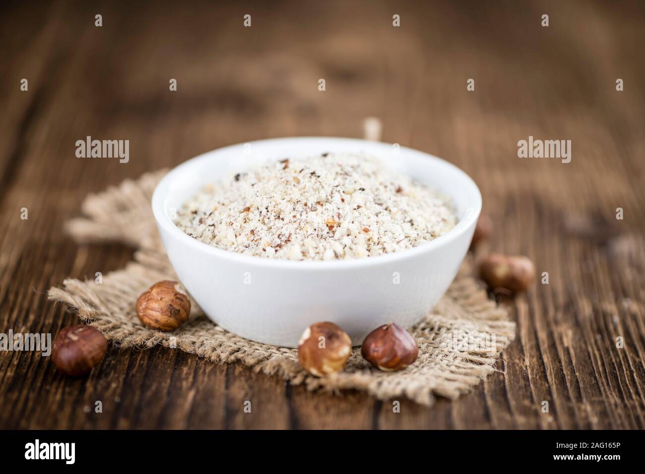 Wooden table with grounded Hazelnuts (close-up shot; selective focus ...