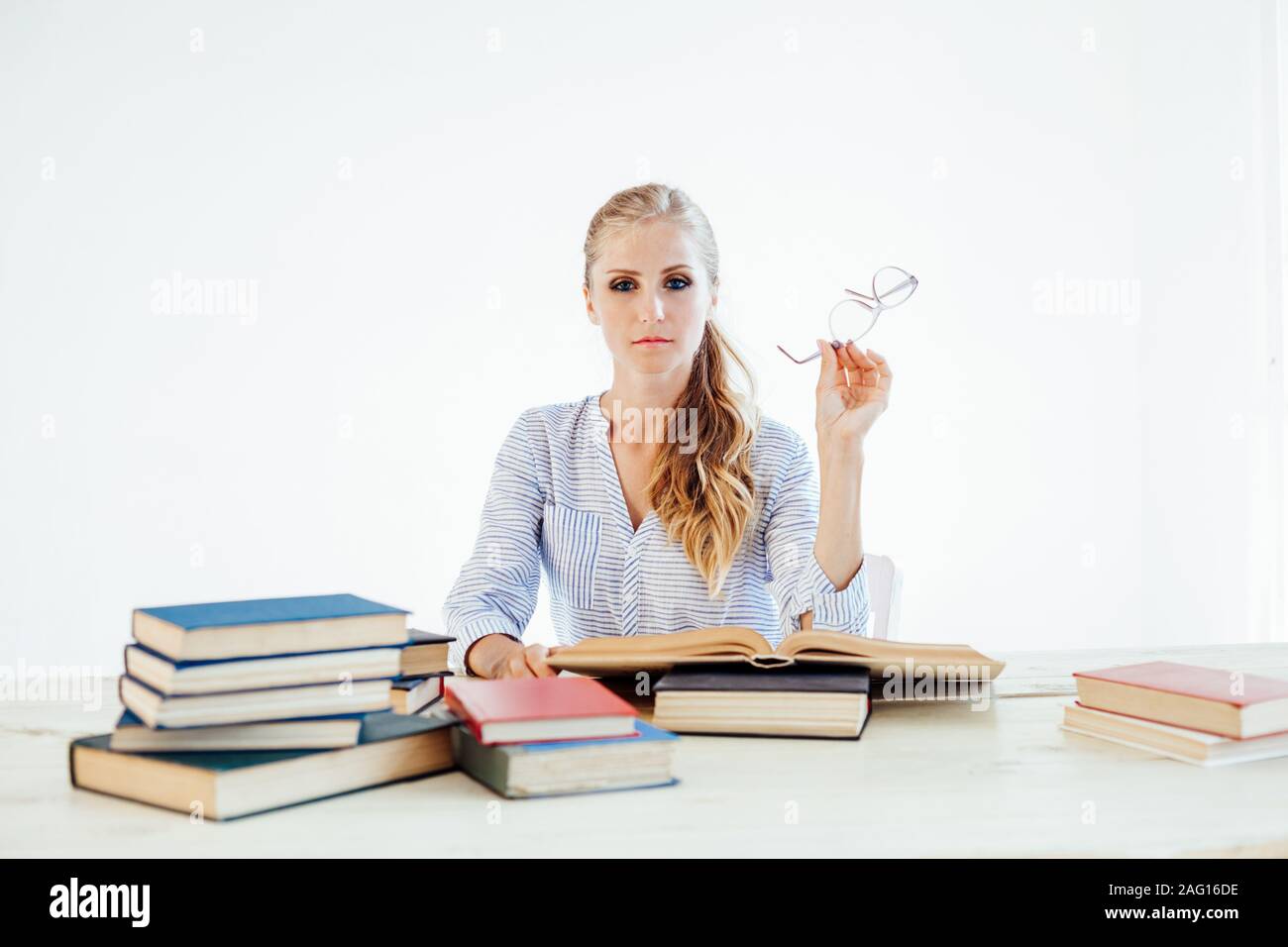 female teacher sitting at a table of many books Office Stock Photo - Alamy