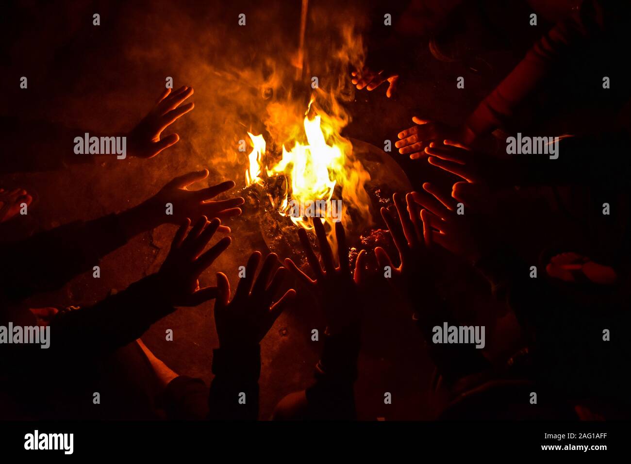 People gather around a bonfire to keep themselves warm on a cold ...