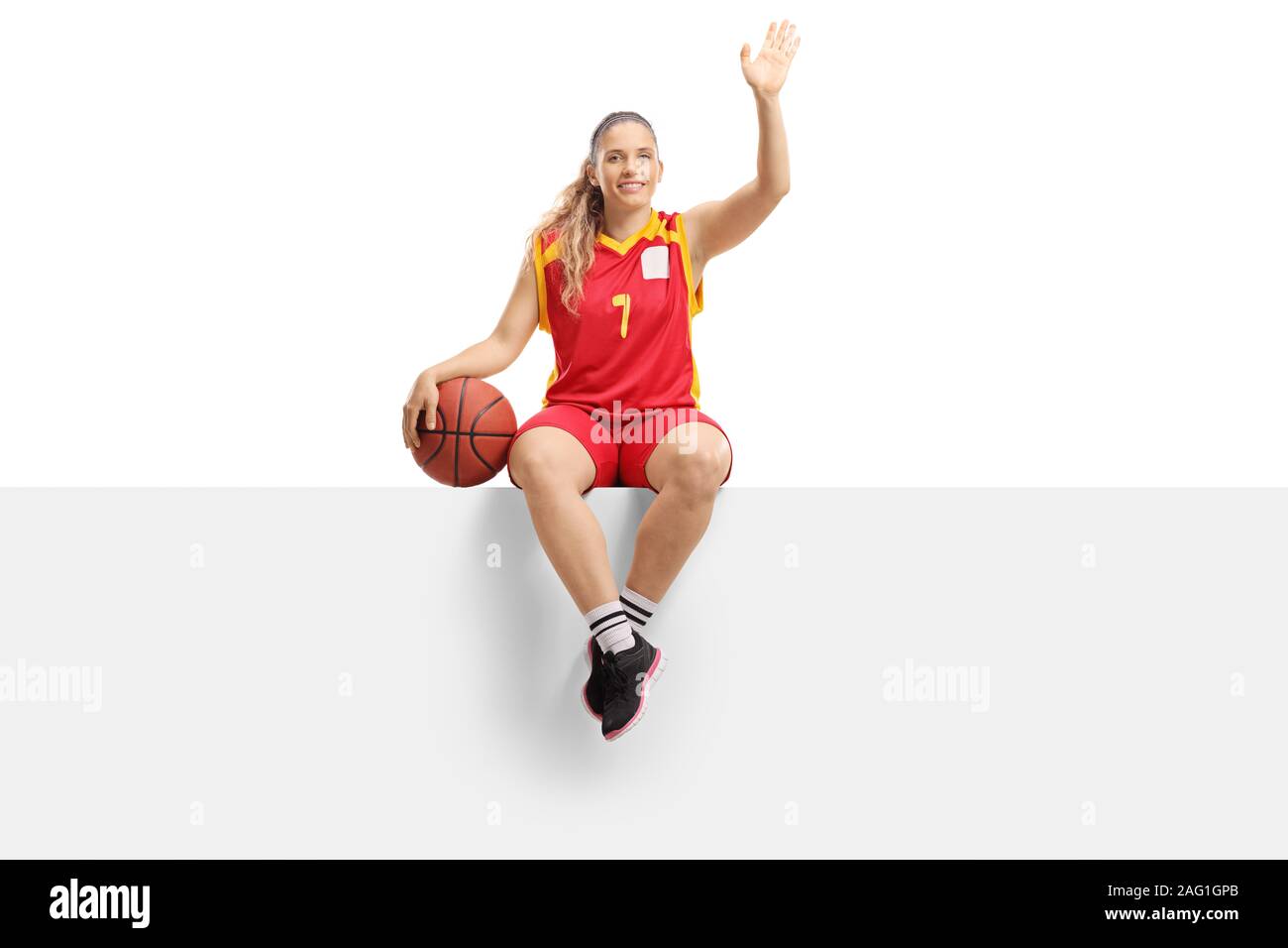 Young female basketball player sitting on a panel and waving at the ...