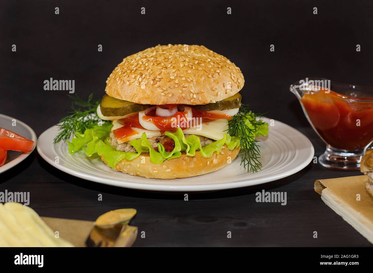 Ready-made hamburger with ingredients on a plate on a black wooden ...