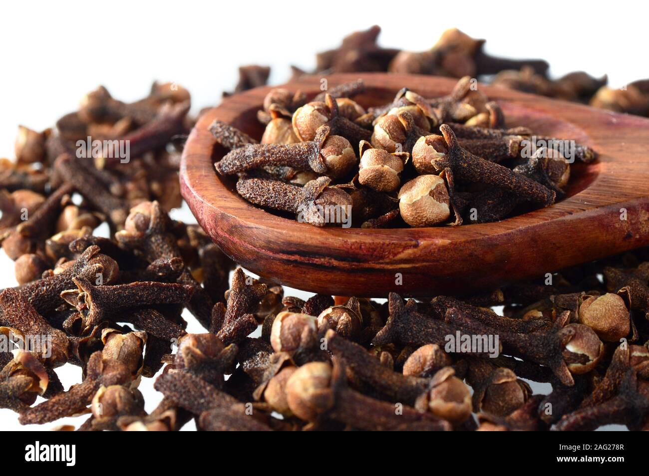 Cloves (spice) and wooden spoon close-up food background. Isolated on white background Stock ...