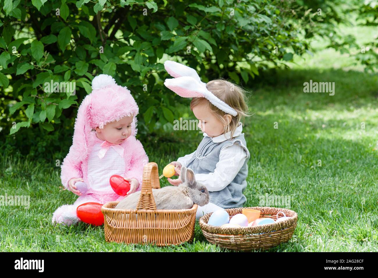 Children play with real rabbit. Laughing child at Easter egg hunt with ...