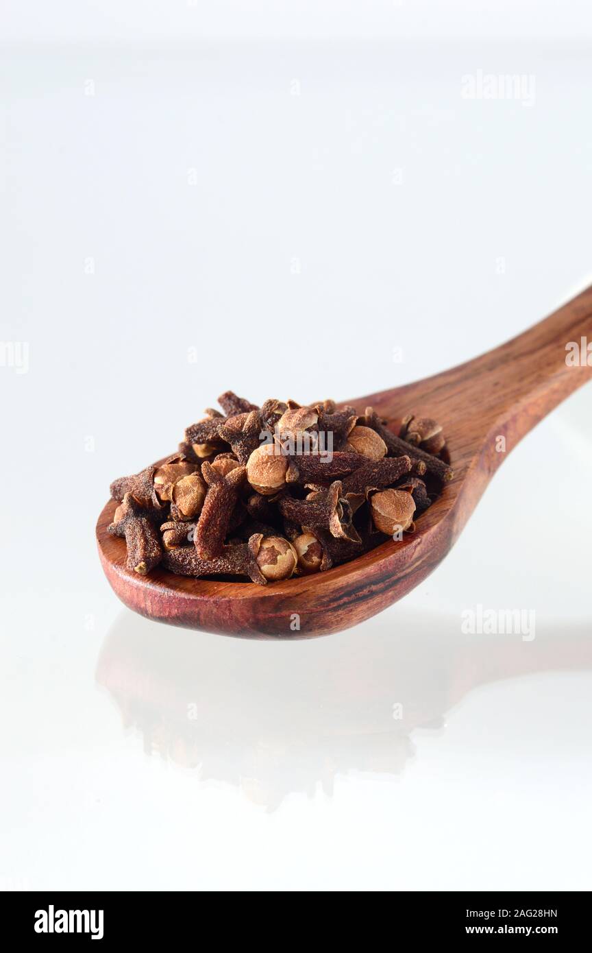Cloves in the white spoon on black background hi-res stock photography ...