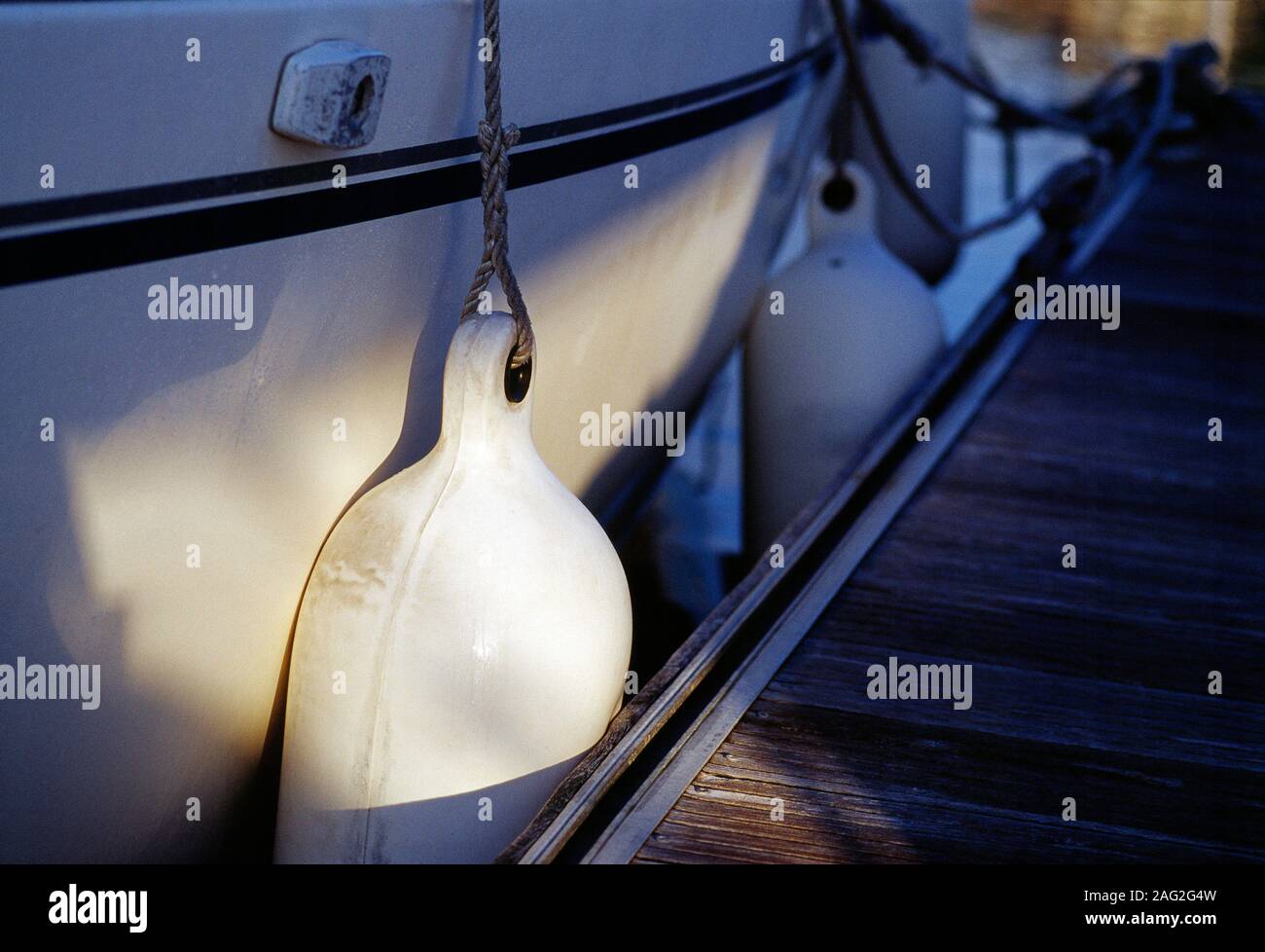 Sailing yacht berthed in marina. Close up of hull with boat fenders and ...
