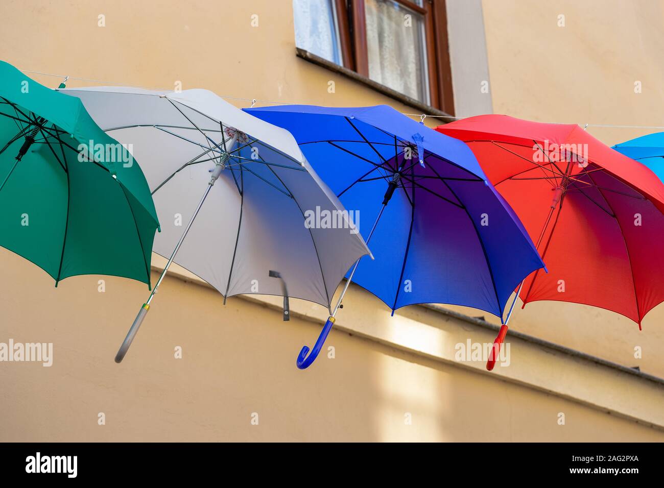 Umbrellas in different colors against the backdrop of a wall on a sunny ...