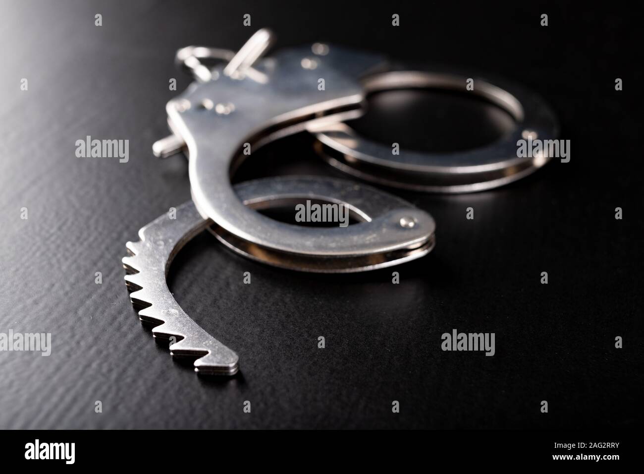 Nickel-plated handcuffs on a black table. Accessories for special ...