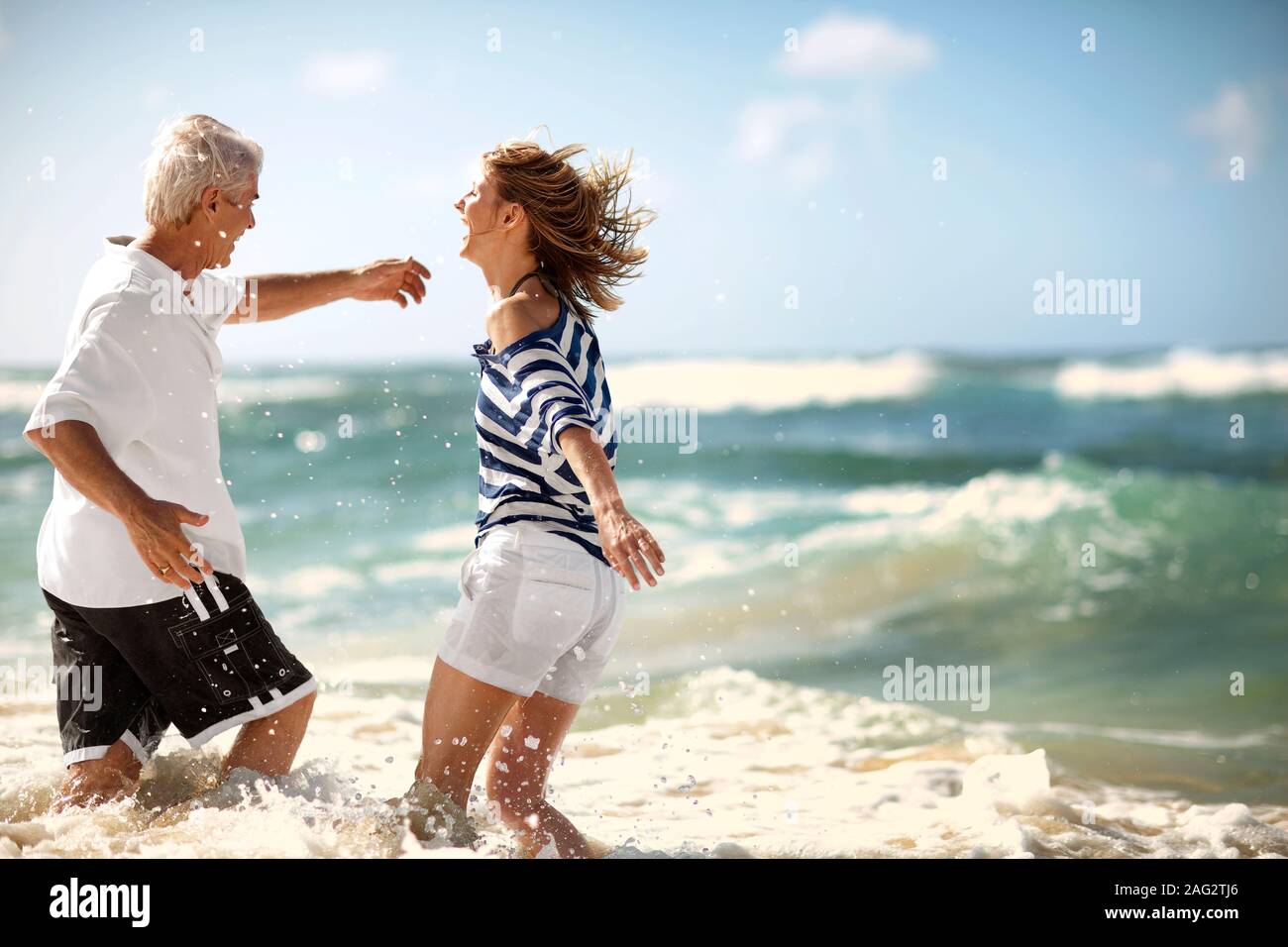 Laughing couple playing in the surf at a beach Stock Photo - Alamy