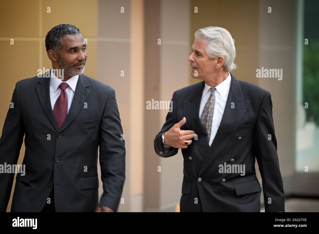 Two businessmen walking and talking Stock Photo - Alamy