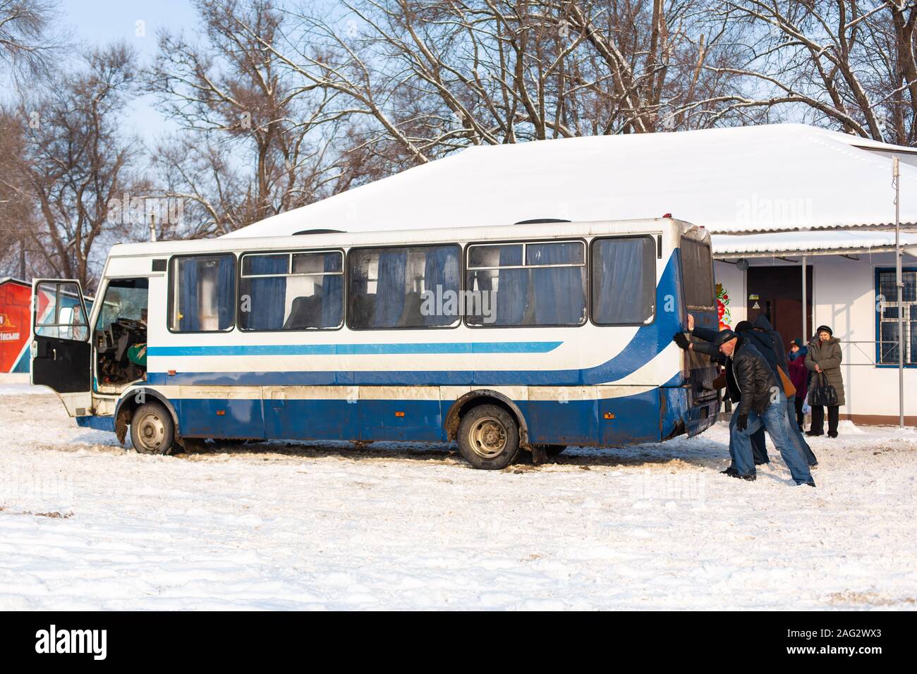 A crowd of people are pushing a bus that is stuck in the snow. Severe ...