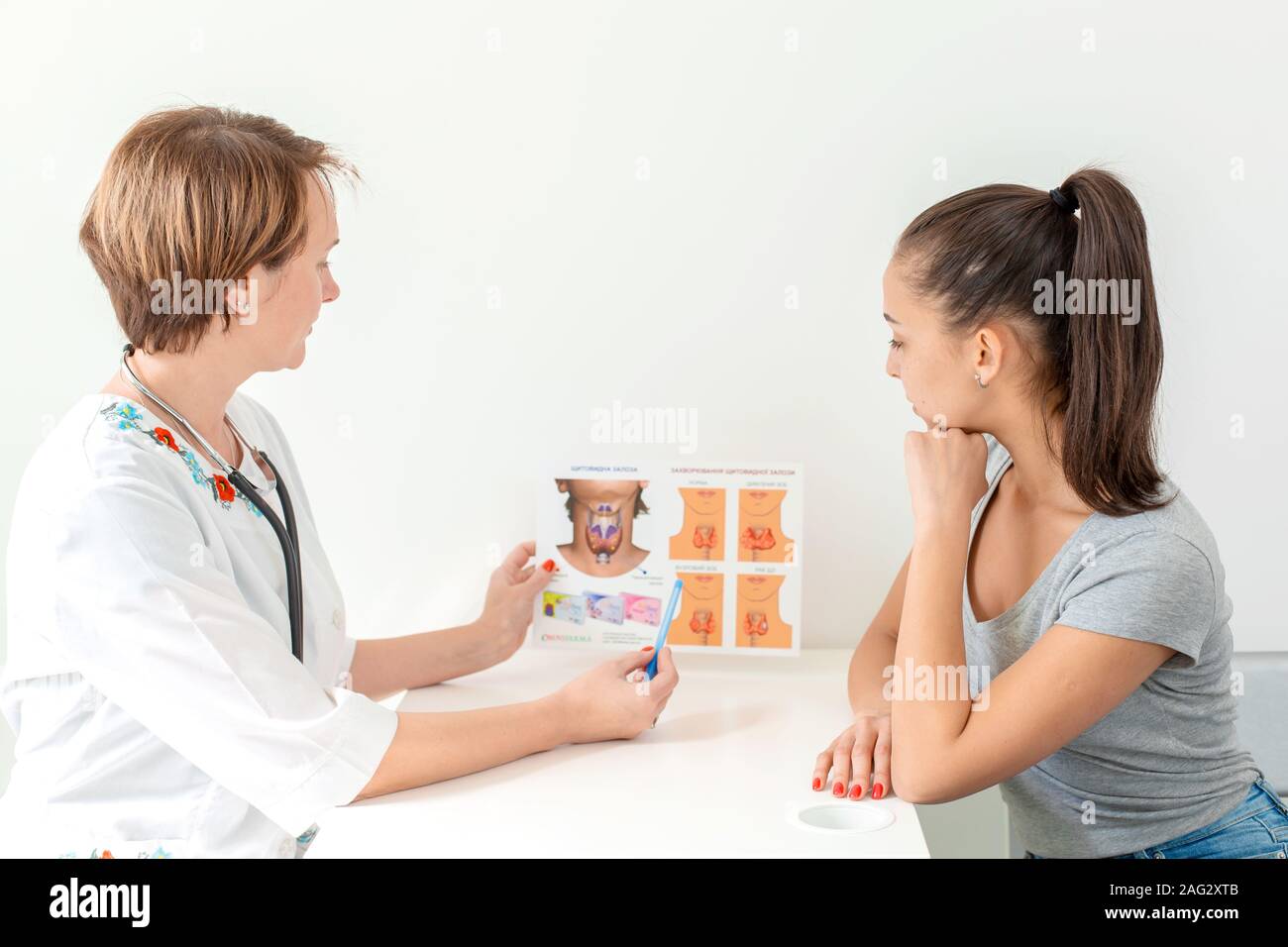 the doctor shows the patient a brochure about the thyroid gland and its ...