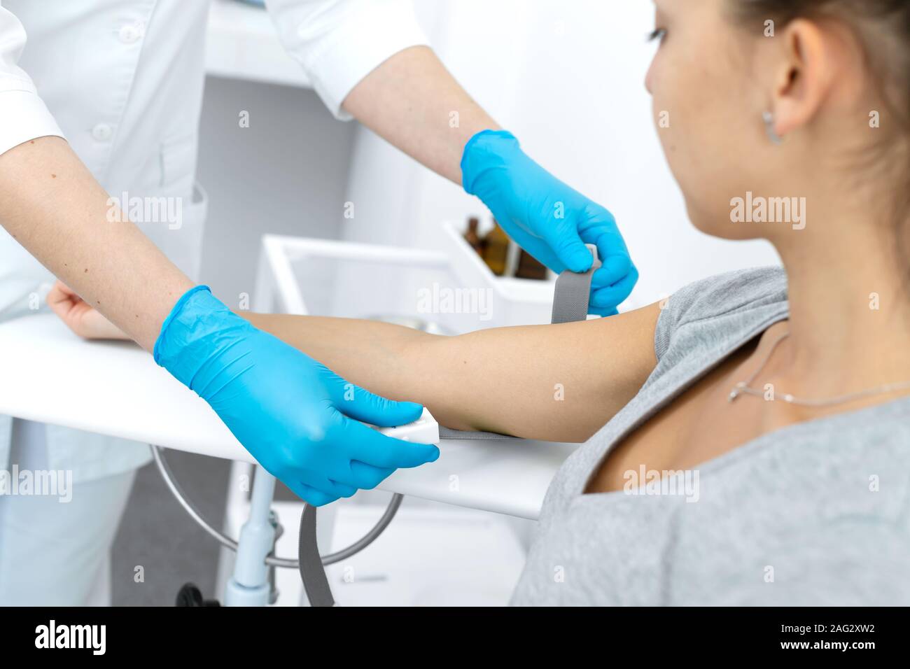 A nurse inserts a needle into a vein on a patient arm. Blood sampling ...