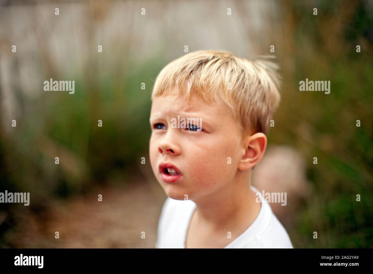 Young boy standing in a garden looking confused Stock Photo - Alamy
