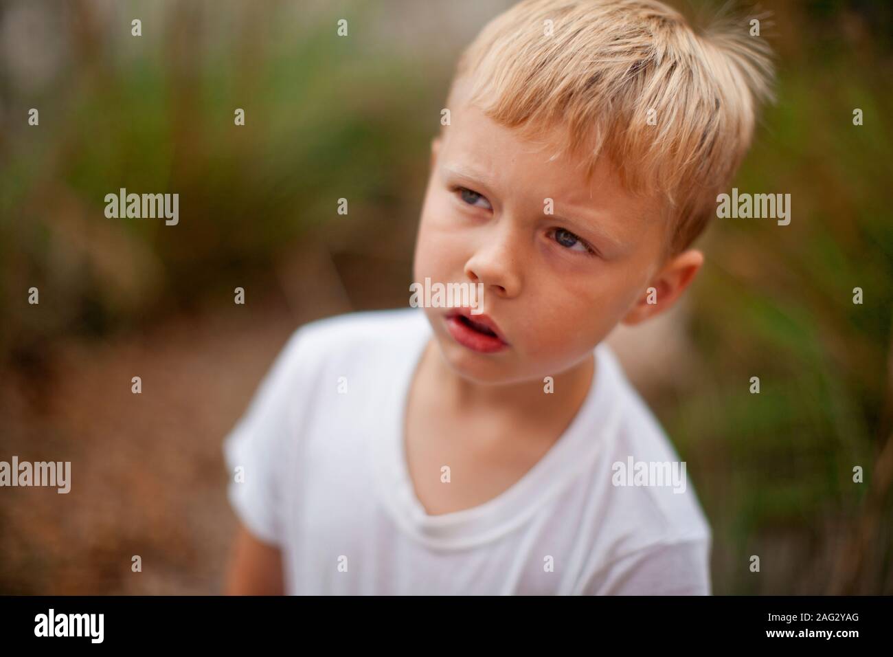 Young boy standing in a garden looking confused Stock Photo - Alamy