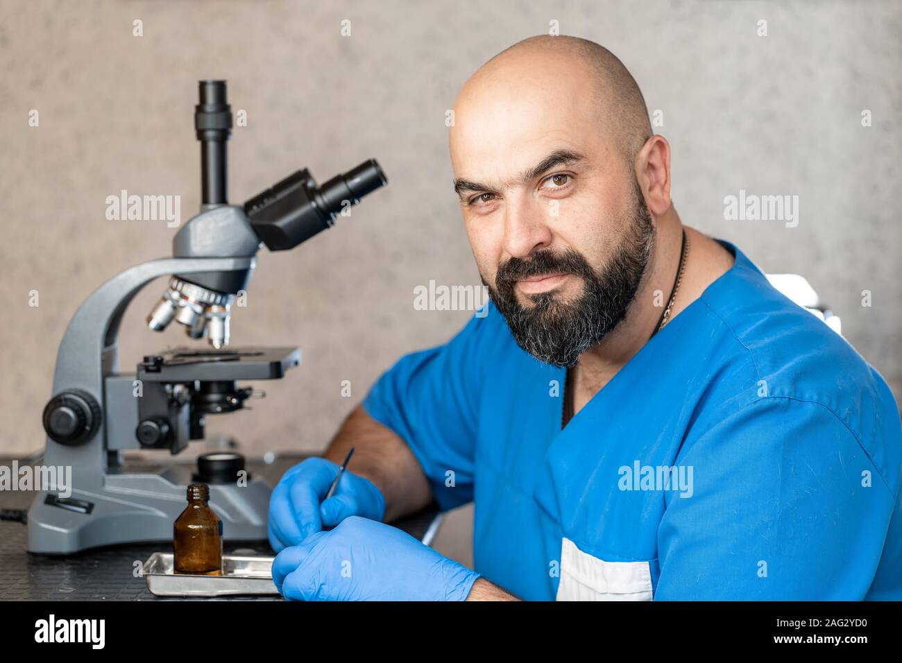 Male laboratory assistant examining biomaterial samples in a microscope ...