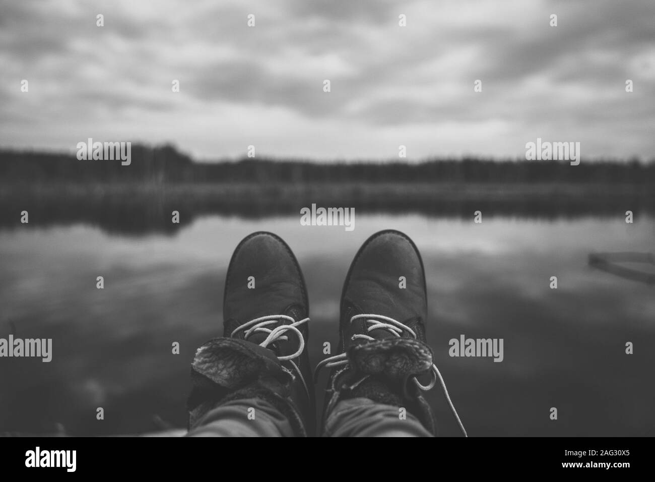 Greyscale selective focus shot of male legs wearing winter boots ...