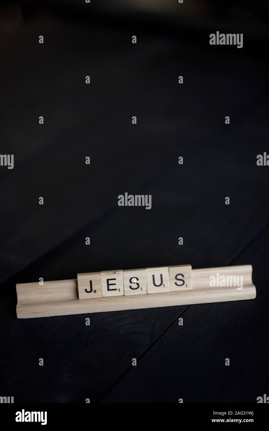 Vertical shot of wooden blocks spelling out Jesus on a black wooden ...