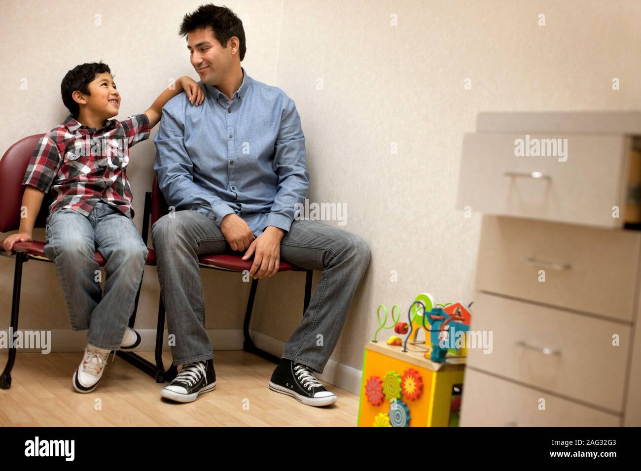 Boy sitting in the hospital waiting room with his father Stock Photo ...