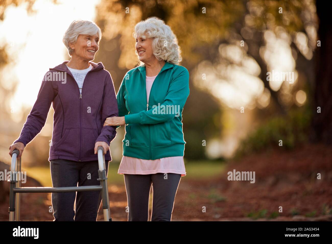 Smiling senior woman helping her friend to walk with a walking aid ...