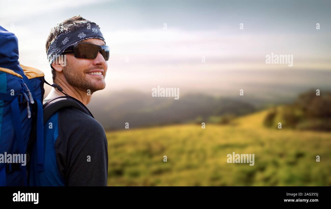 Young backpacker grins back over his shoulder as he prepares to set out ...