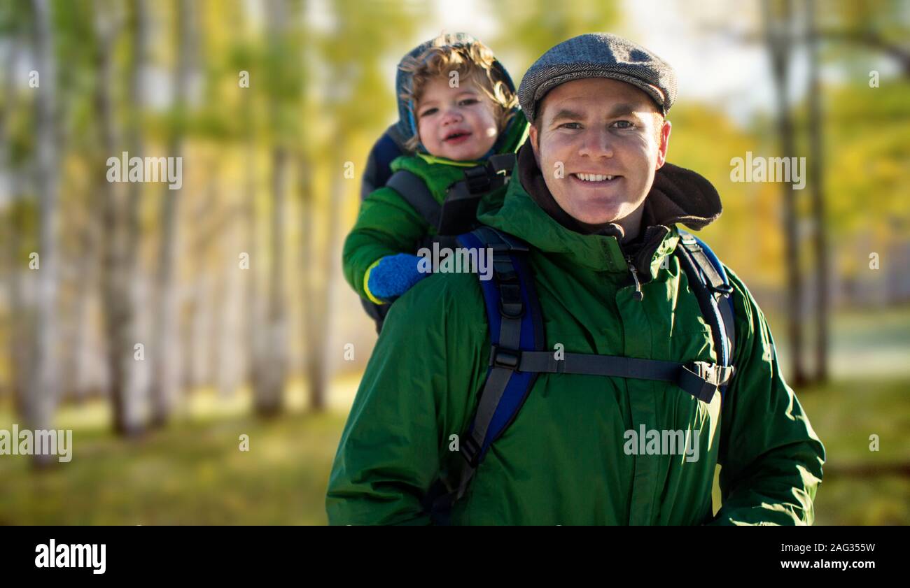 Portrait of a smiling father carrying his adorable baby son in a ...