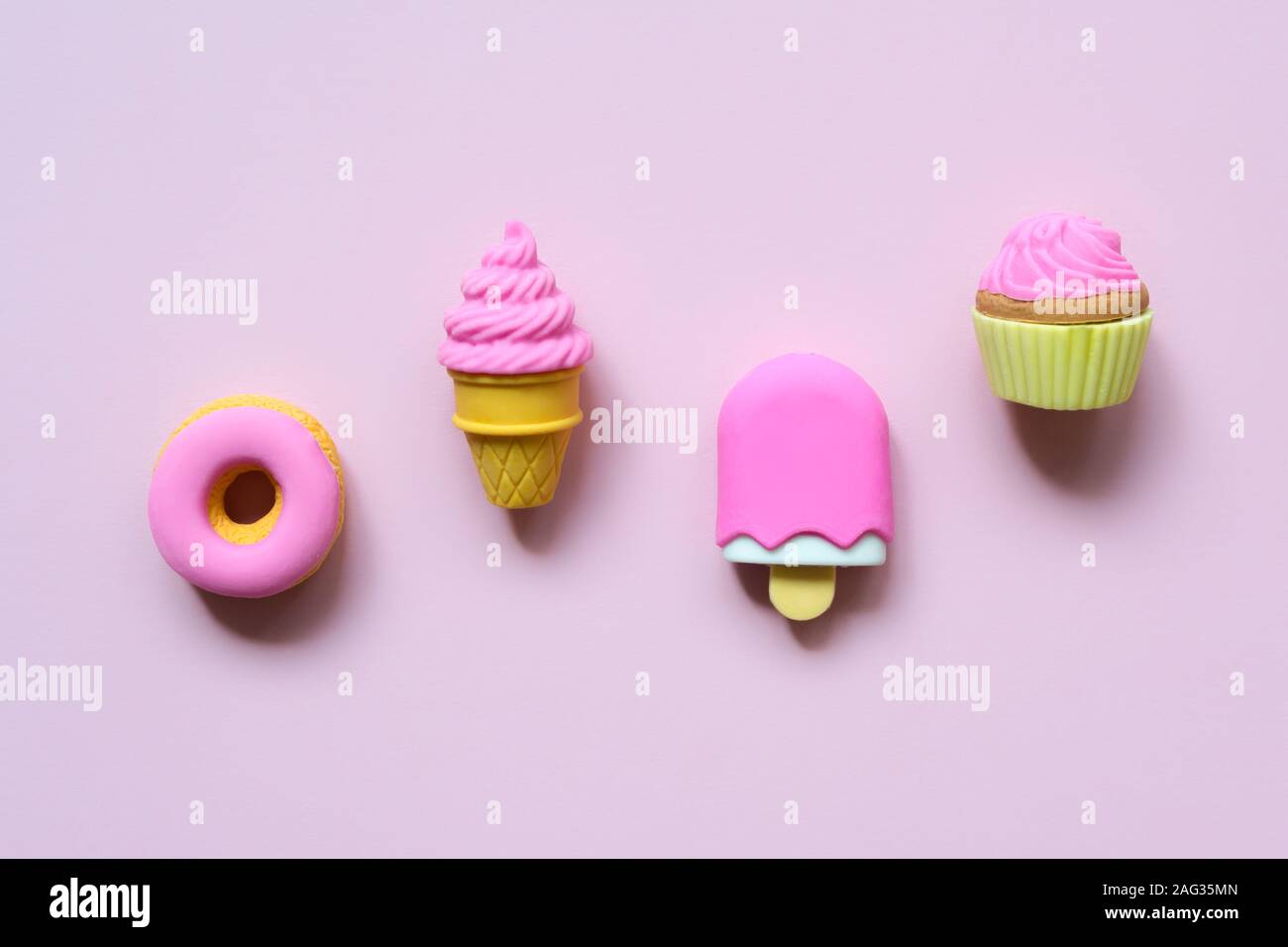 Different toy sweets in miniature with shadows close-up on a soft pink ...