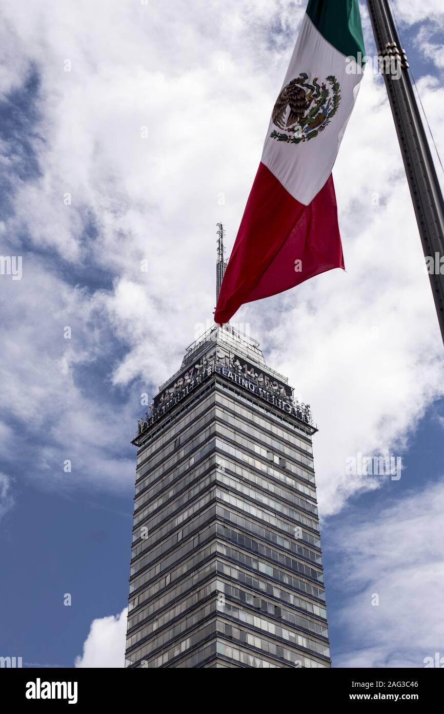 Vertical shot of the flag of Mexico waving over a high rise building ...