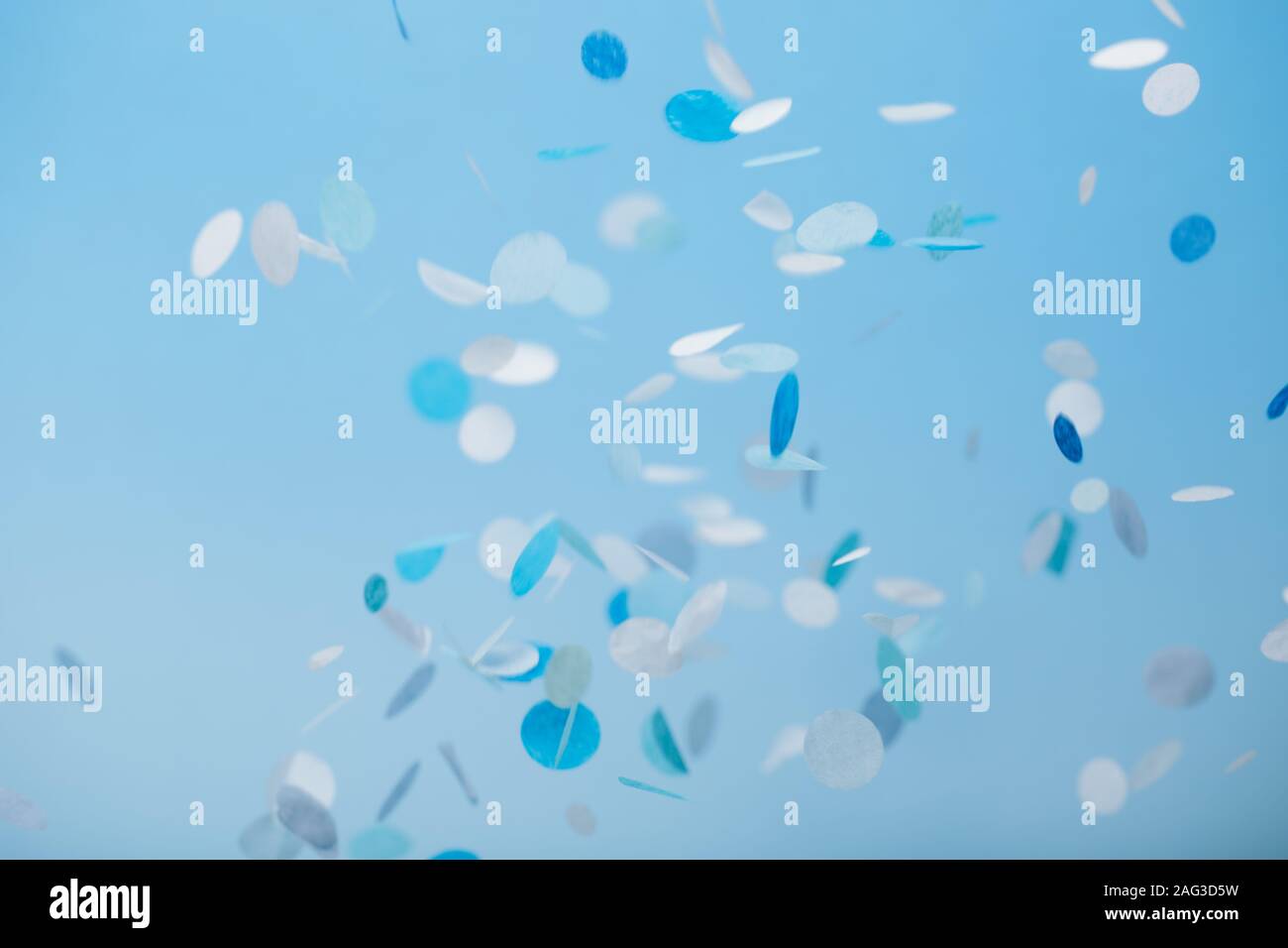 Blue falling confetti on pastel blue background Stock Photo - Alamy