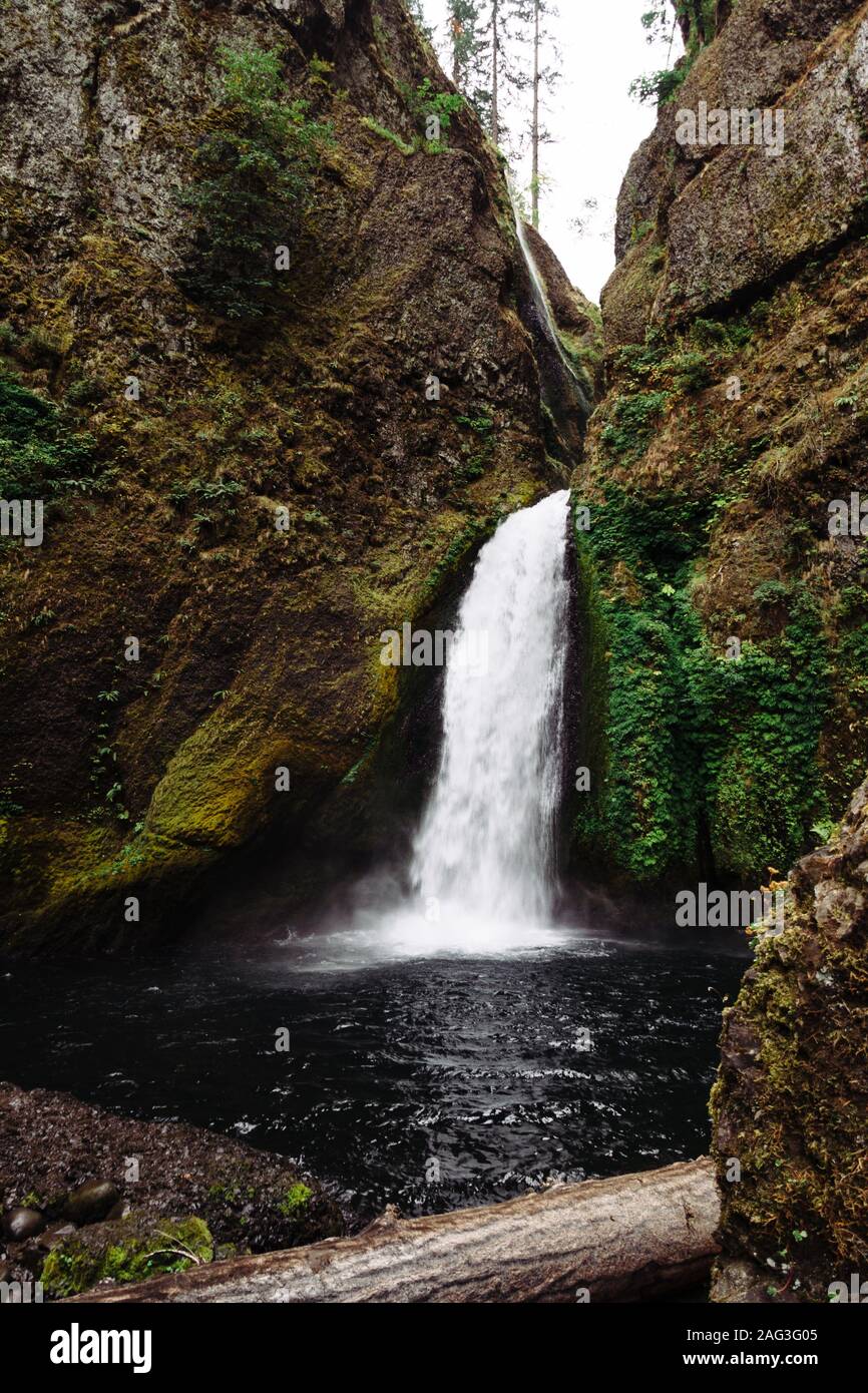Strong waterfall falling from the middle of enormous rocks and flowing ...