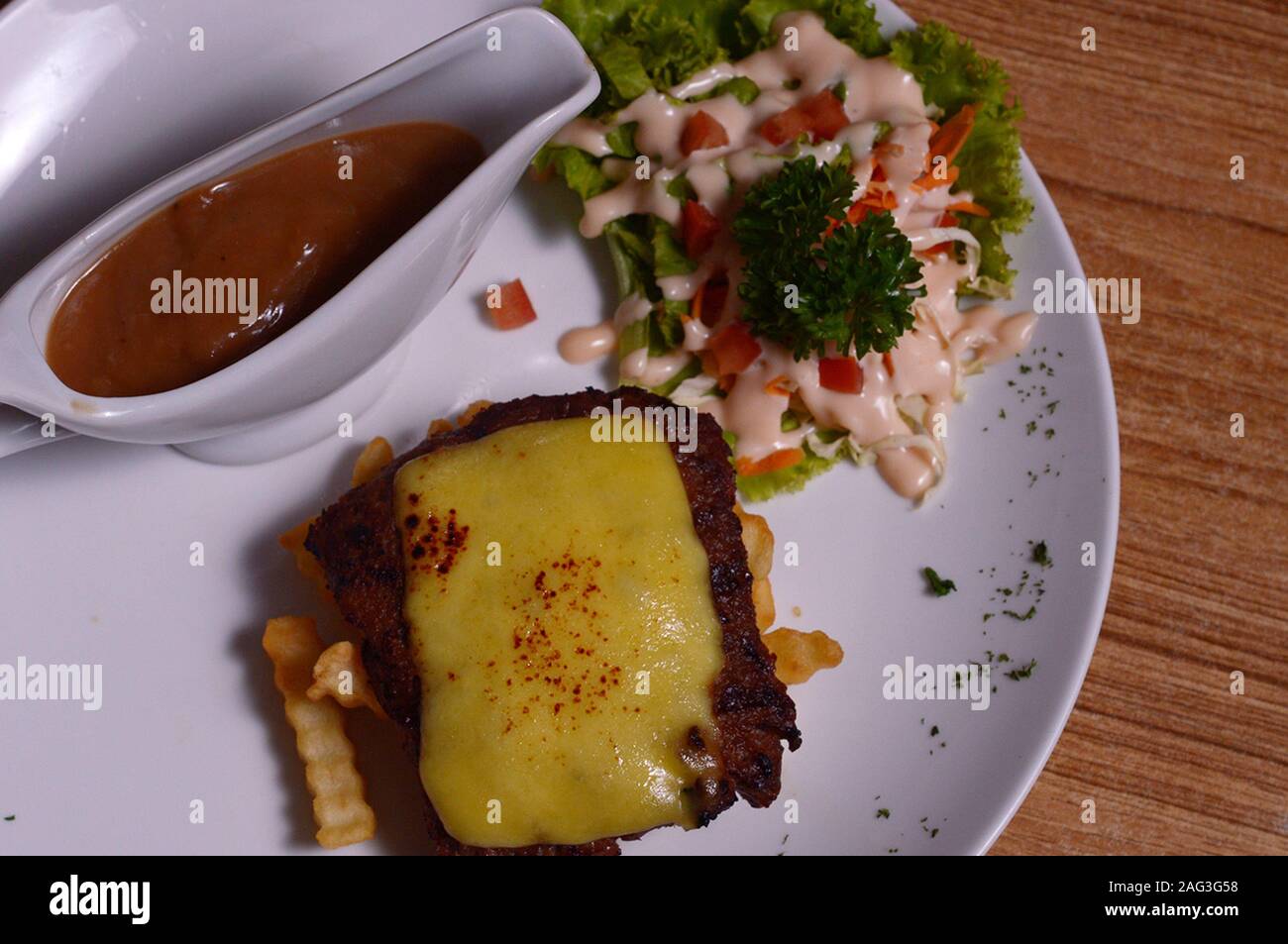 High angle shot of a plate with melted cheese on beef and a salad Stock ...