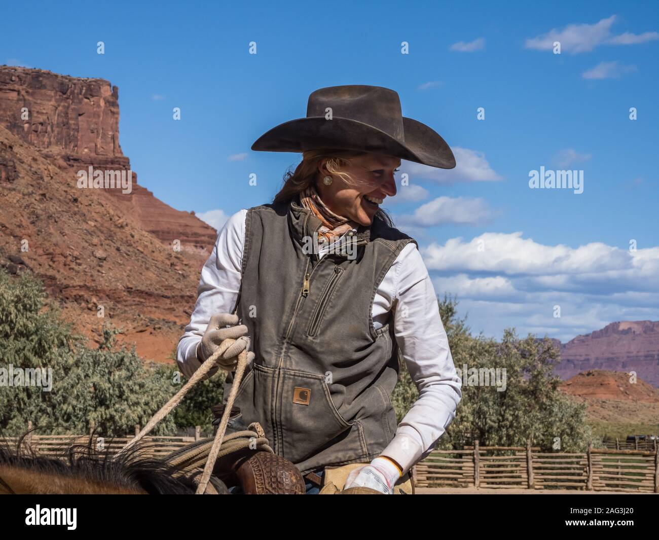 A young, attractive working cowgirl wrangler on her horse on a ranch ...