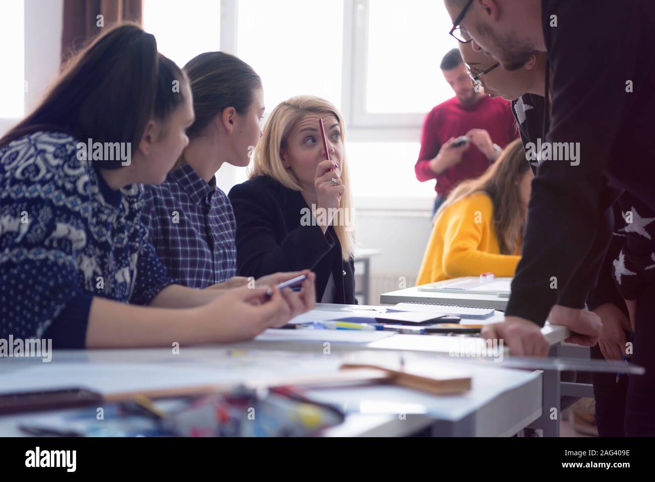 Beautiful young female teacher helping a student during class. Female ...