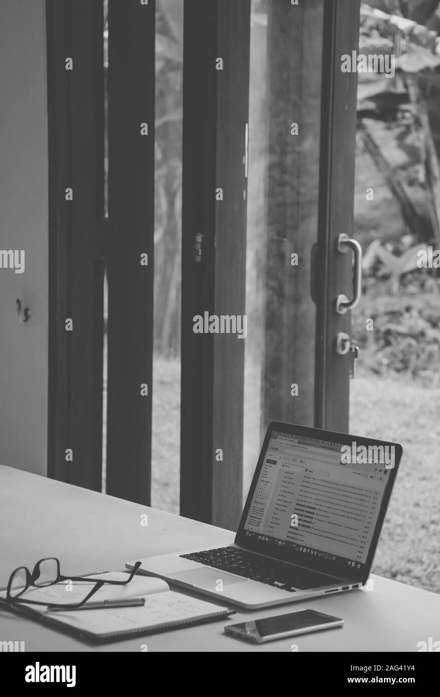 Vertical gray scale of a laptop with books and a glasses with a ...