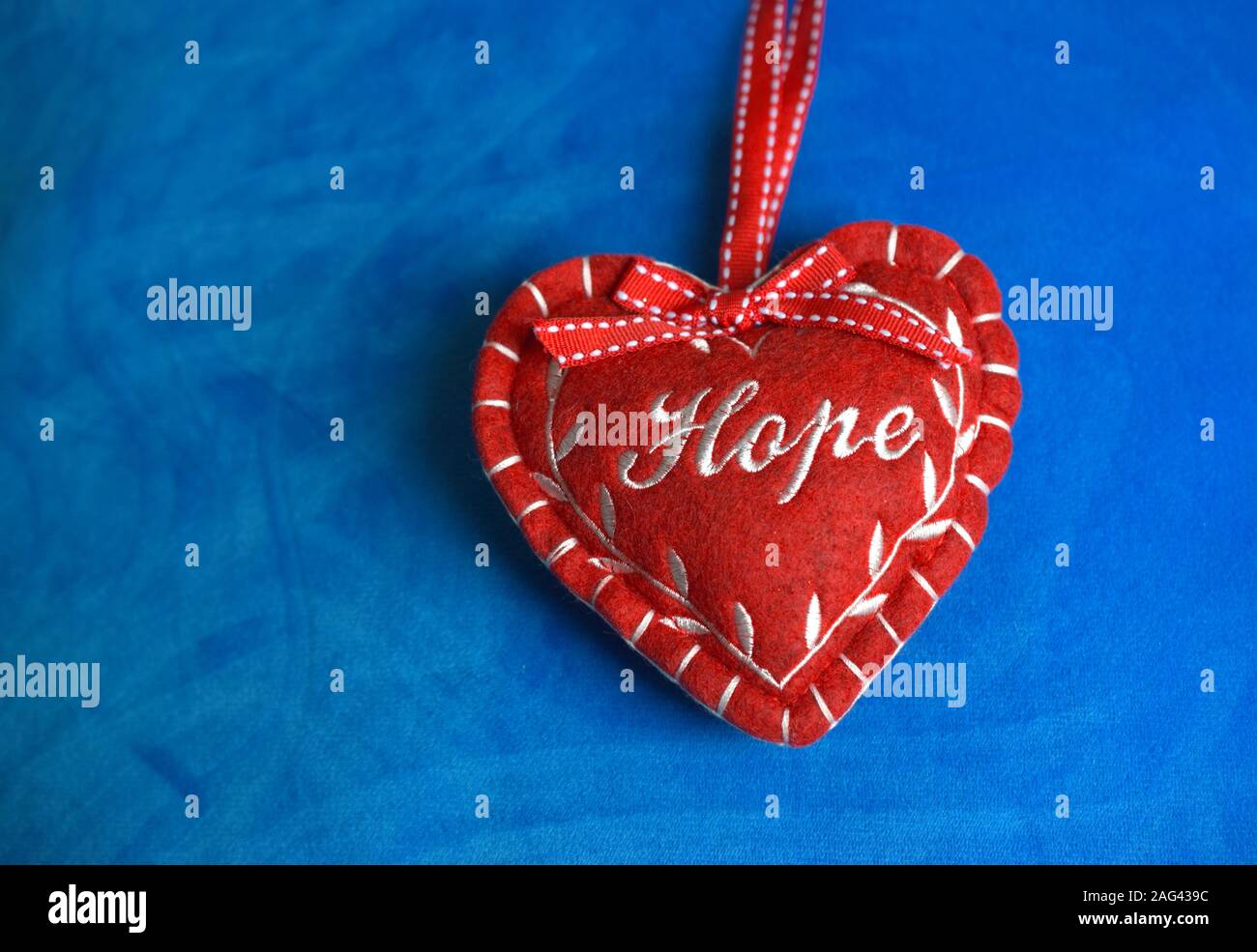 Handmade red textured heart with embroidered word hope on blue ...