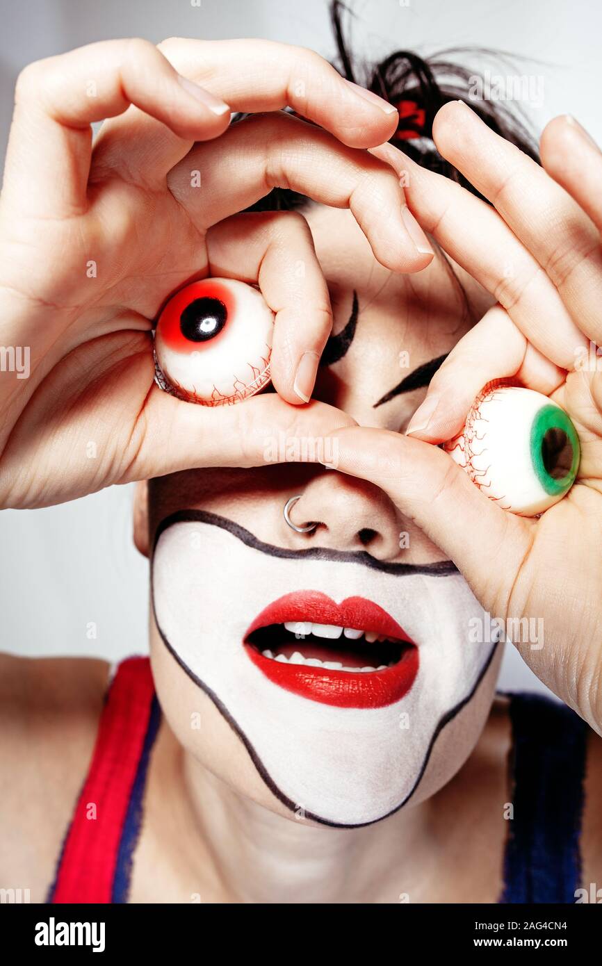 Vertical shot of a clown with painted mouth holding shapes of red and ...