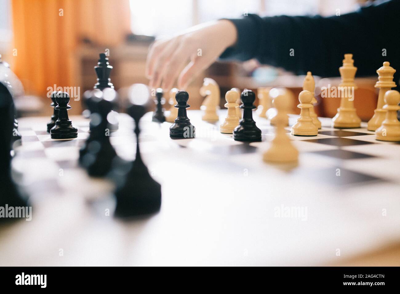 Low angle blurred shot of chess figures on a desk and an arm replacing ...