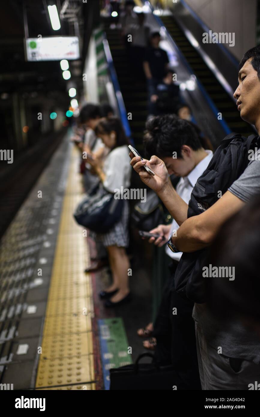 Group of people using mobile phones while waiting for subway train ...