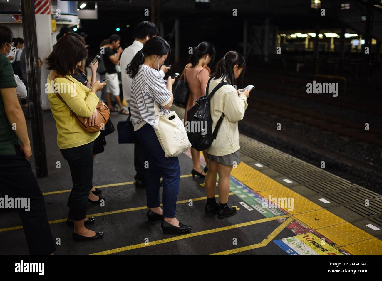 Group of people using mobile phones while waiting for subway train ...