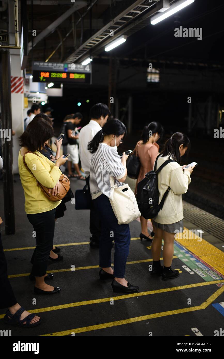 Group of people using mobile phones while waiting for subway train ...