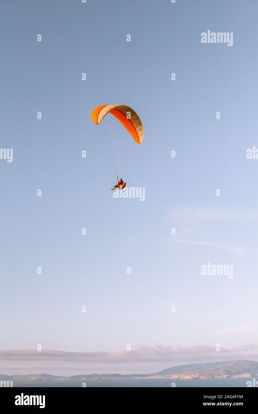 Vertical shot of a lonely person parachuting down under the beautiful ...