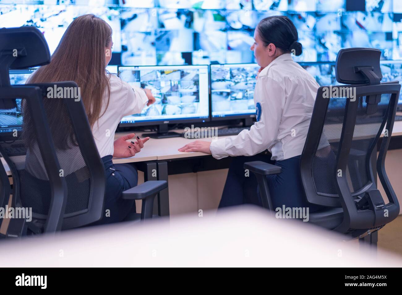 Security guard monitoring modern CCTV cameras in surveillance room. Two ...
