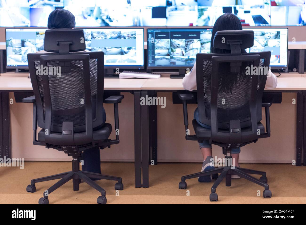 Security guard monitoring modern CCTV cameras in surveillance room. Two ...