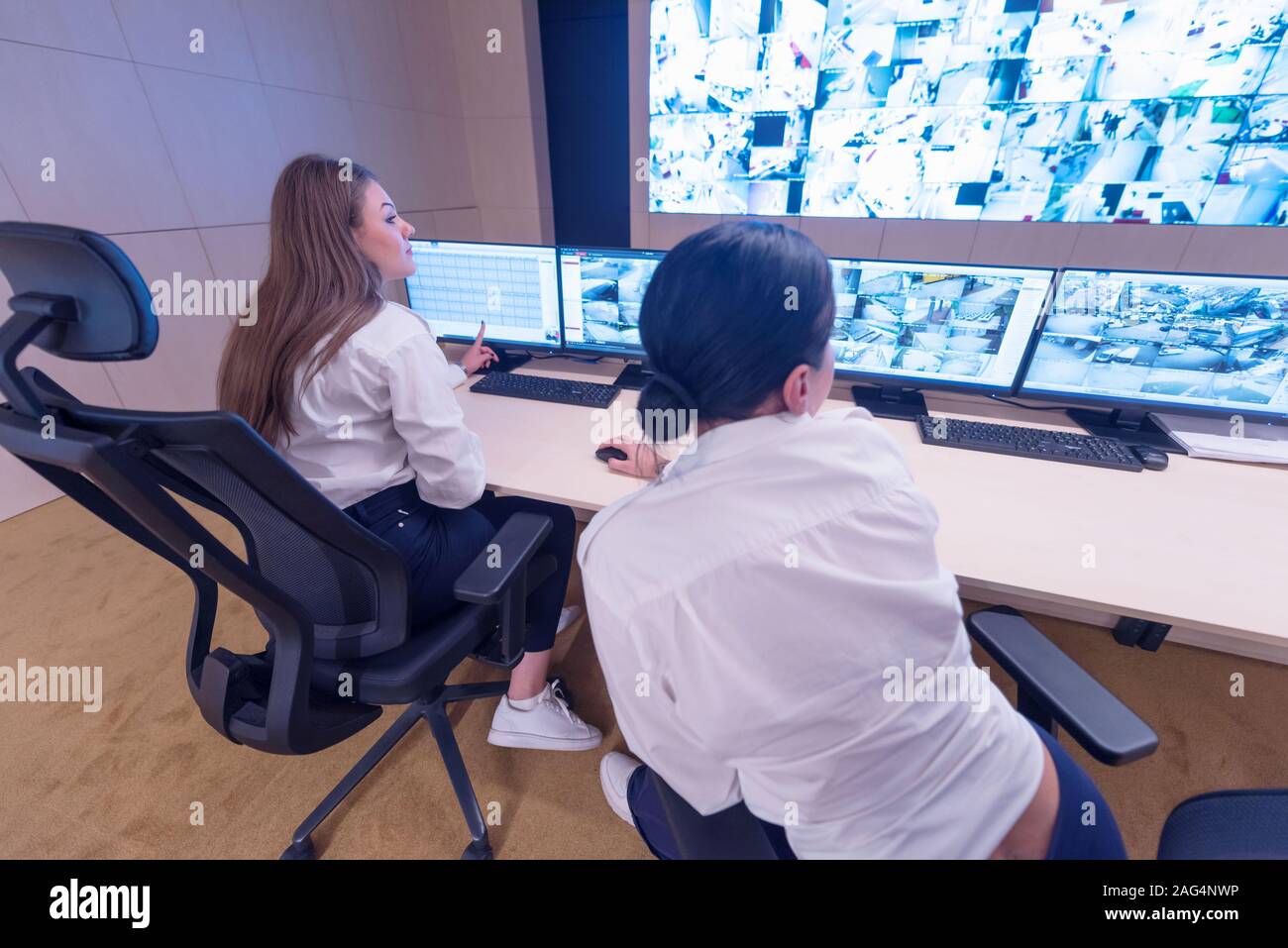 Security guard monitoring modern CCTV cameras in surveillance room. Two ...