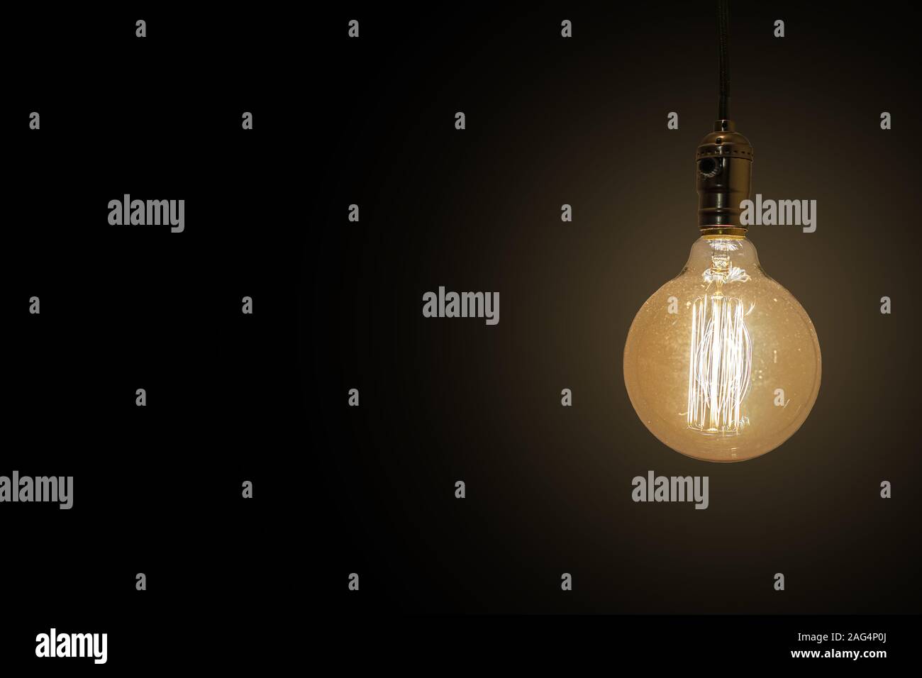 Closeup shot of an old lit light bulb isolated on a black background ...