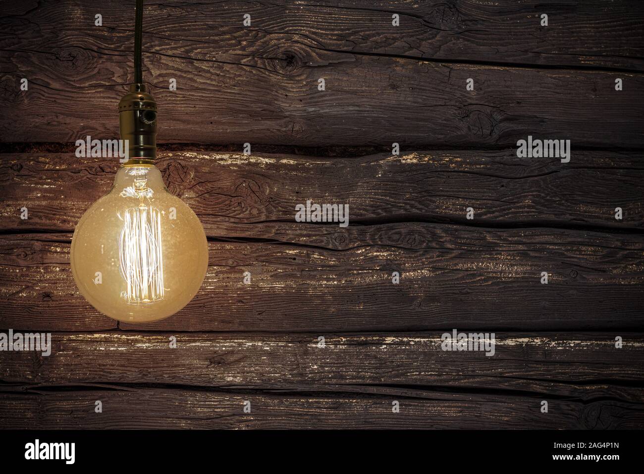 Old vintage yellow electric lightbulb spreading light on wooden ...