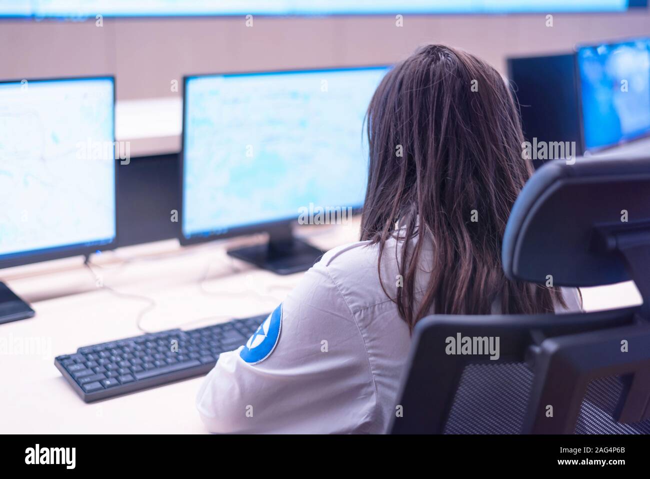 Female security guard working on computers while sitting in the main ...