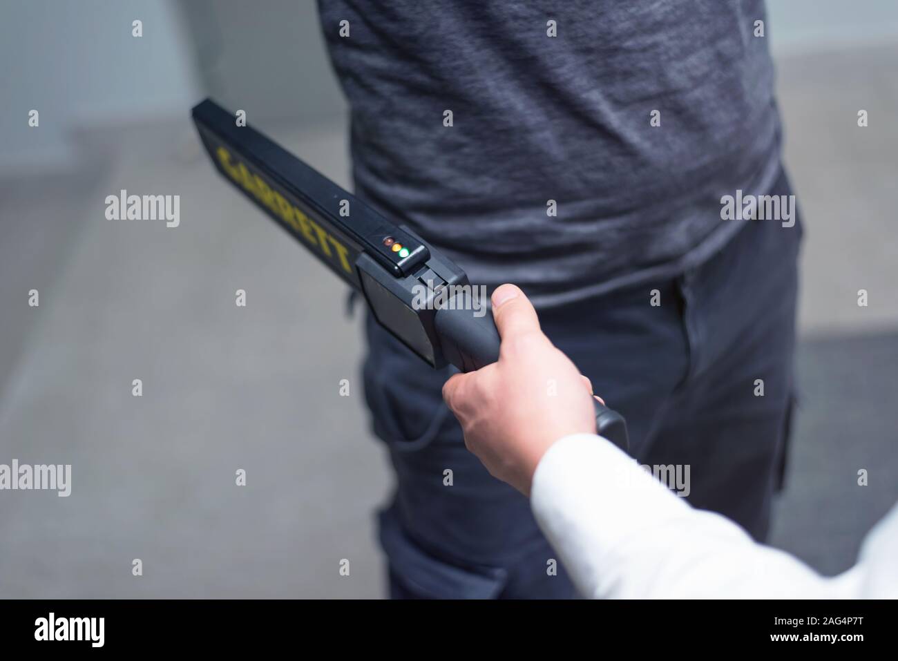 Guard with a metal detector checking a man for weapons and metal ...